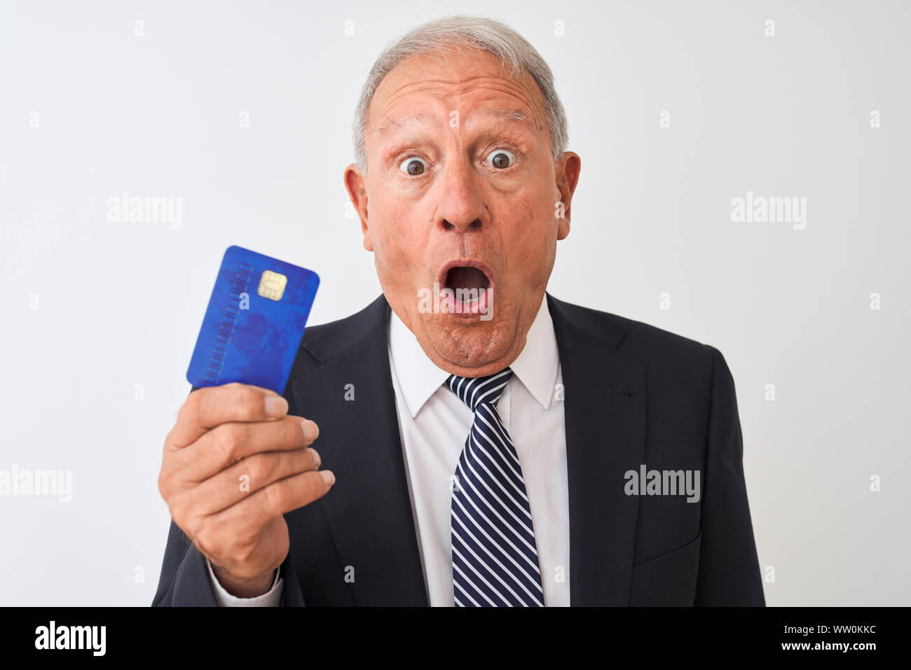 Senior grey-haired businessman holding credit card over isolated white ...