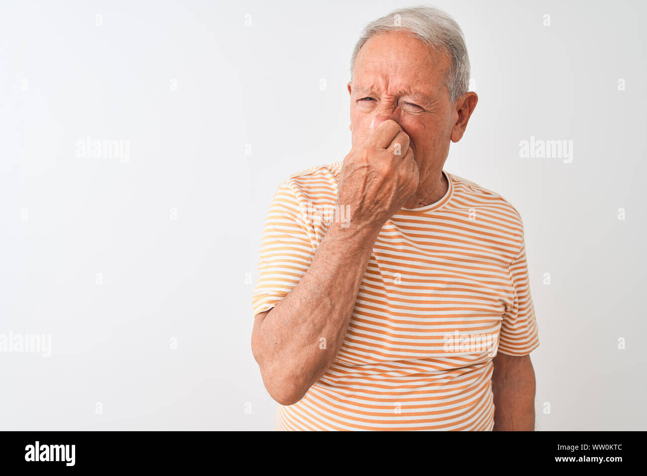 Senior grey-haired man wearing striped t-shirt standing over isolated ...