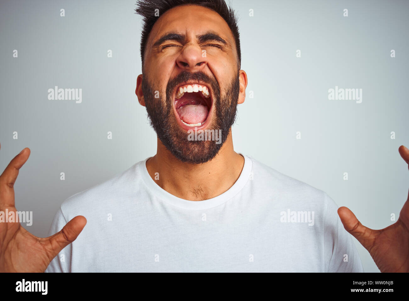 Young indian man wearing t-shirt standing over isolated white ...