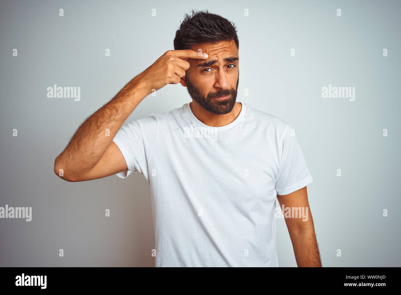 Young indian man wearing t-shirt standing over isolated white ...