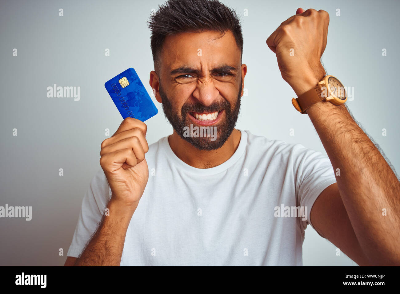 Young indian customer man holding credit card standing over isolated ...