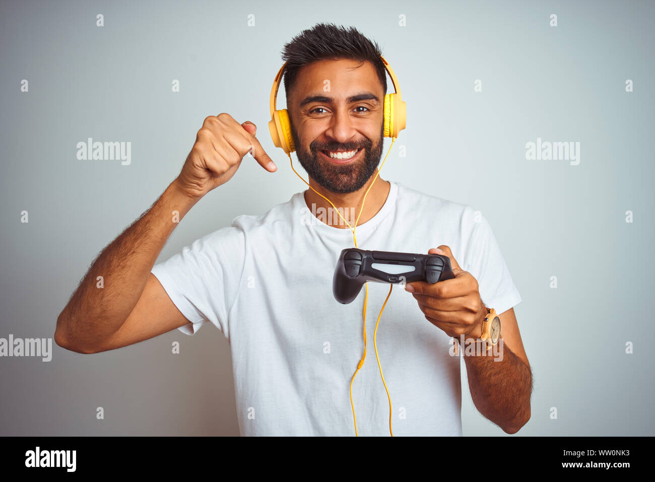 Arab indian gamer man playing video game using headphones over isolated ...