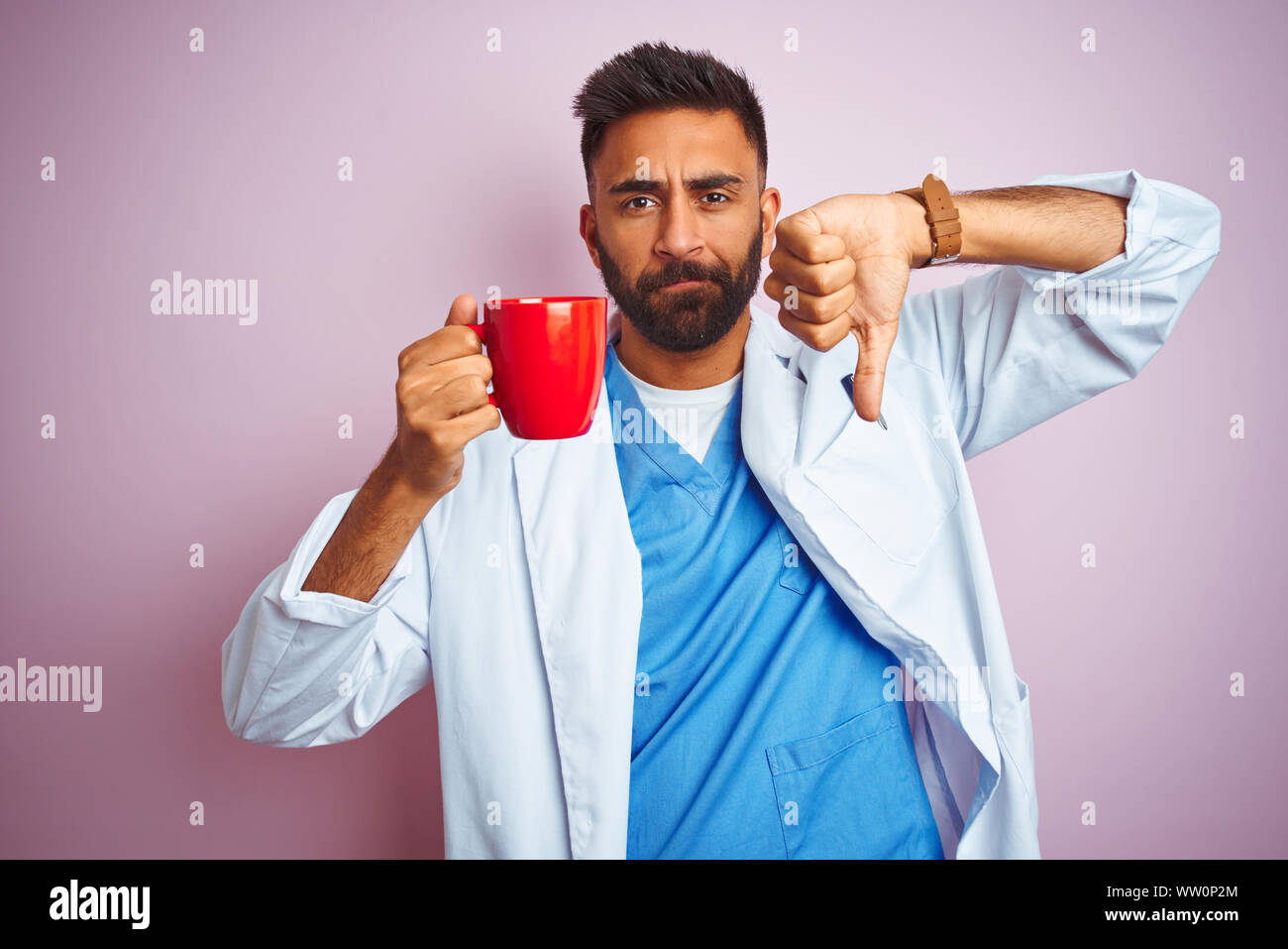 Young indian doctor man drinking cup of coffee standing over isolated ...