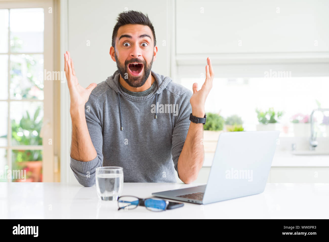 Handsome hispanic man working using computer laptop celebrating crazy ...