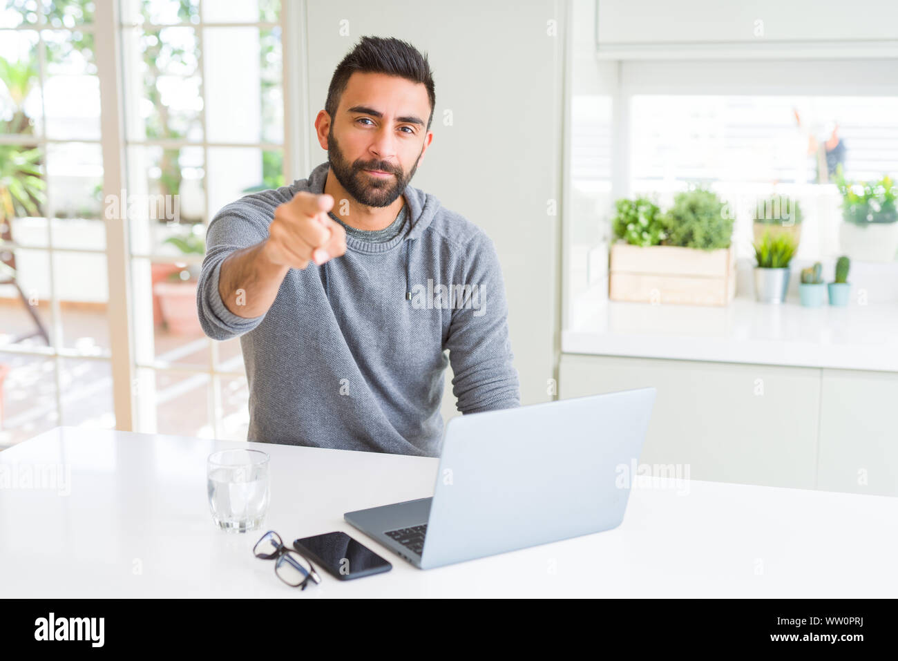 Handsome hispanic man working using computer laptop pointing with ...