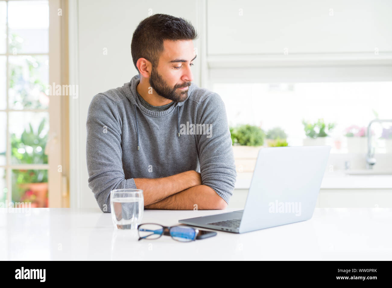 Handsome hispanic man working using computer laptop looking to side ...