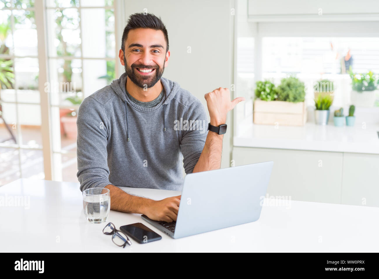 Handsome hispanic man working using computer laptop pointing and ...