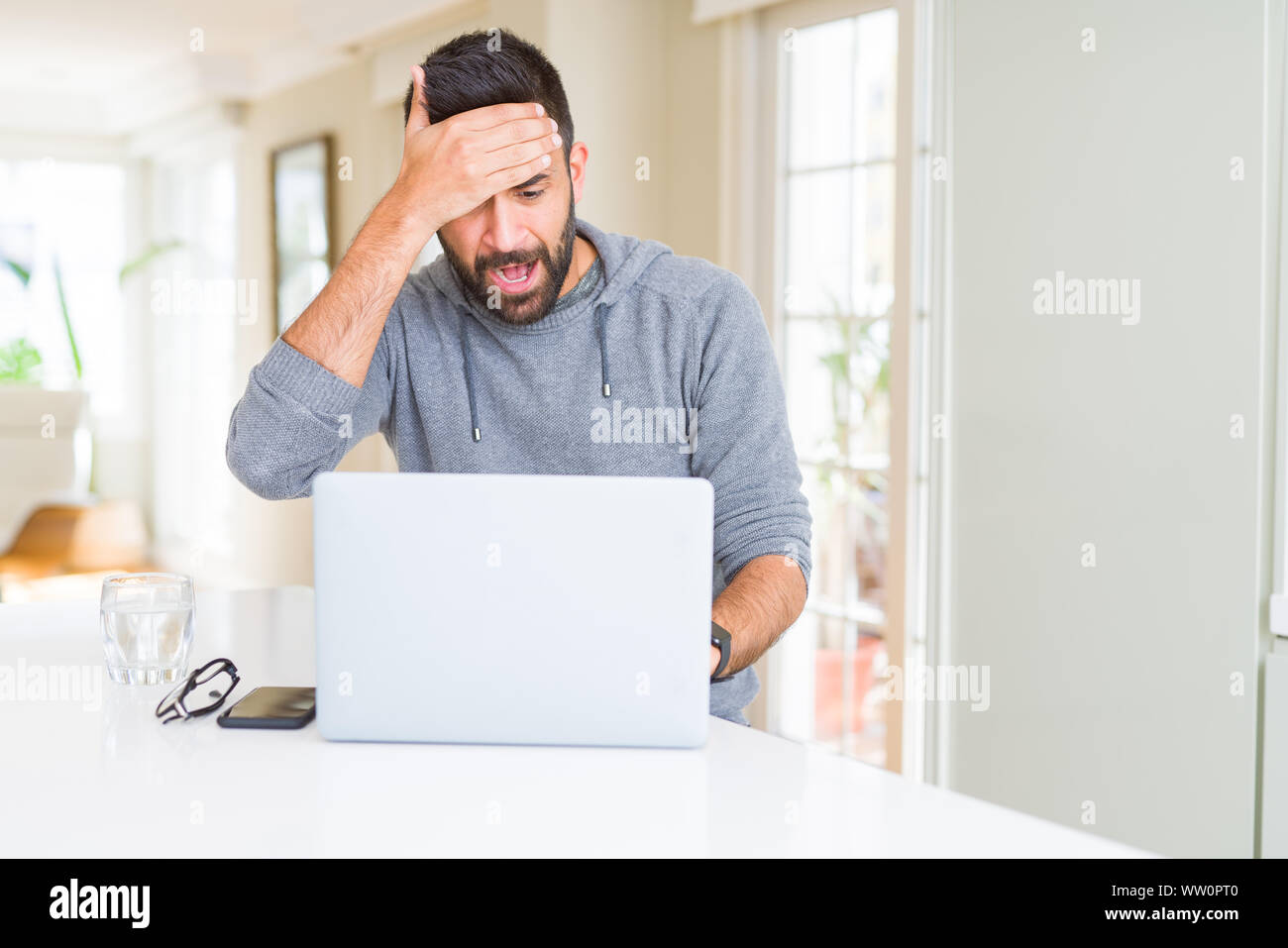 Handsome hispanic man working using computer laptop stressed with hand ...