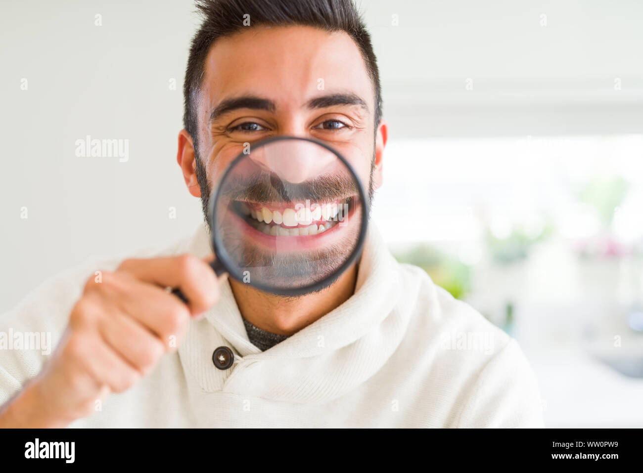 Handsome man using magnifying glass, doing funny faces Stock Photo - Alamy