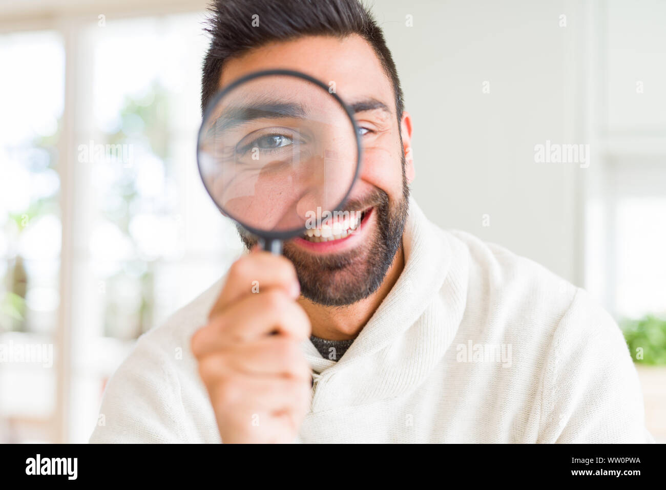 Handsome man using magnifying glass, doing funny faces Stock Photo - Alamy