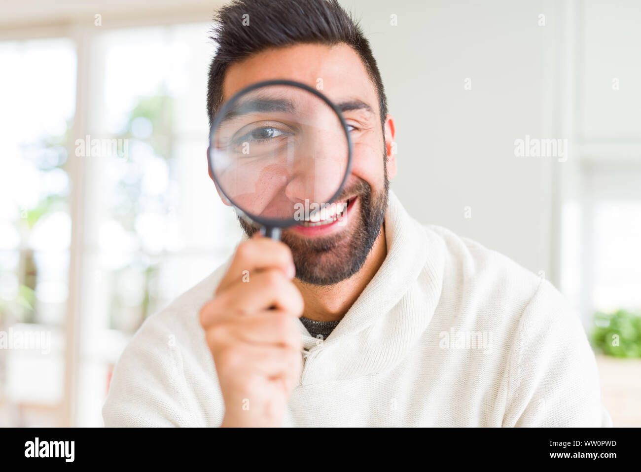 Handsome man using magnifying glass, doing funny faces Stock Photo - Alamy