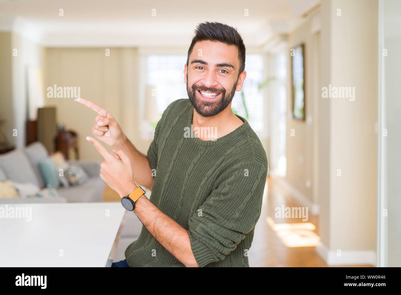 Handsome man pointing with arms and fingers, smiling cheerful with big ...