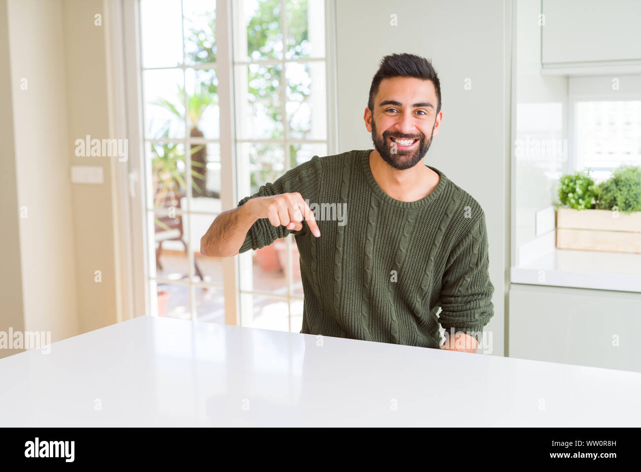 Handsome man pointing with arms and fingers, smiling cheerful with big ...