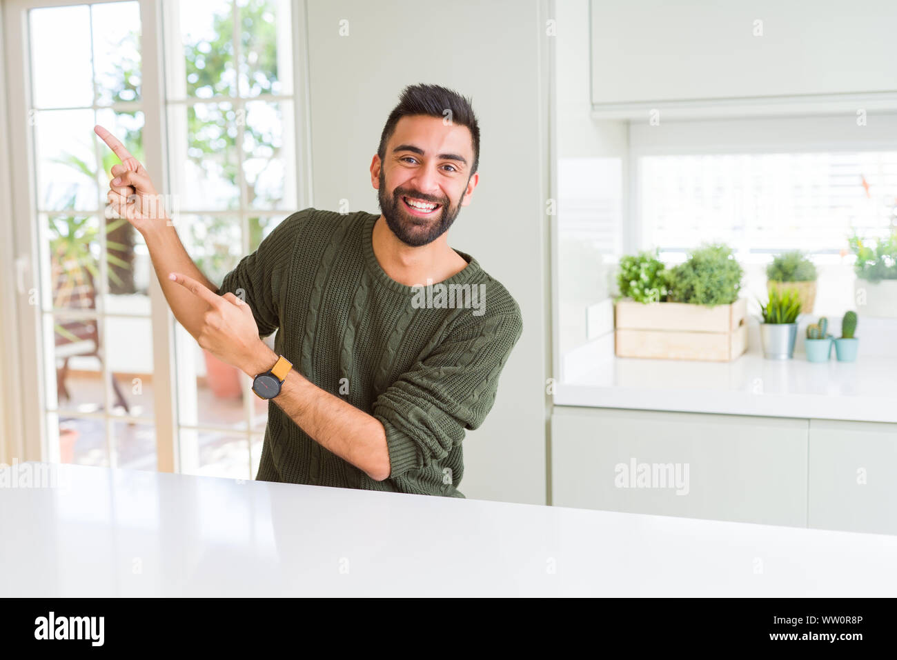 Handsome man pointing with arms and fingers, smiling cheerful with big ...