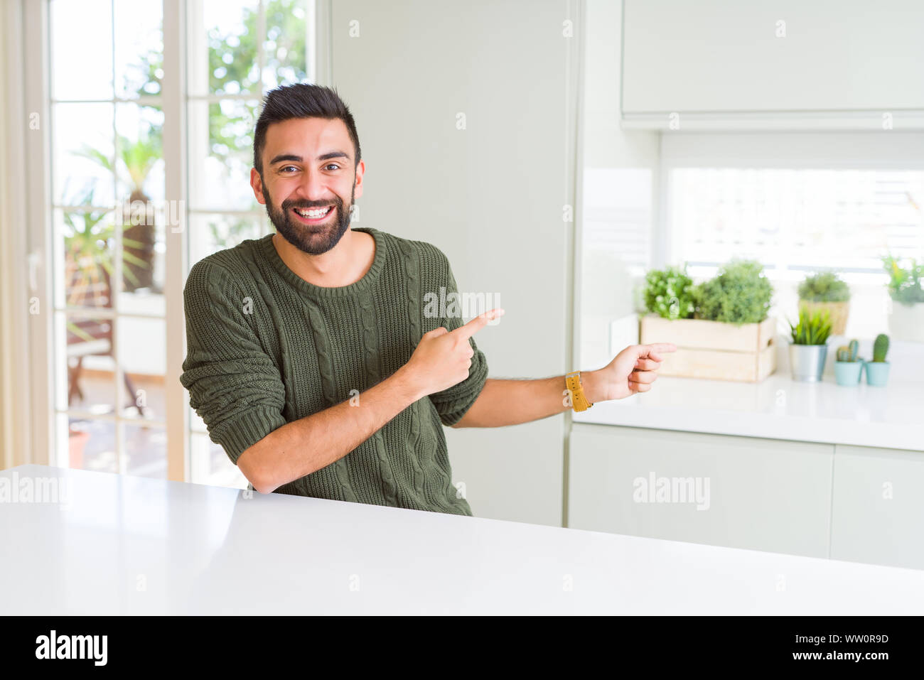 Handsome man pointing with arms and fingers, smiling cheerful with big ...