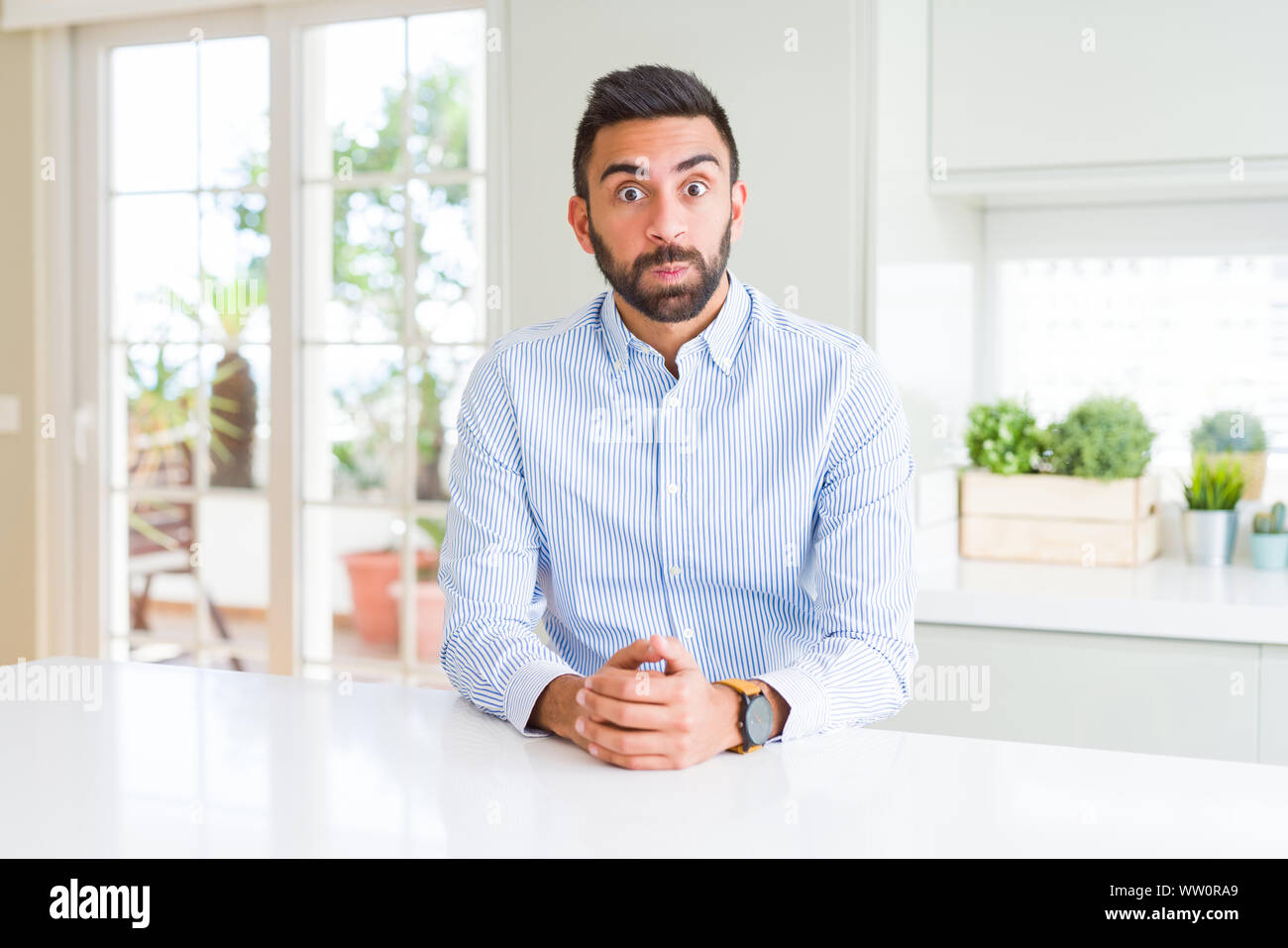 Handsome hispanic business man puffing cheeks with funny face. Mouth ...