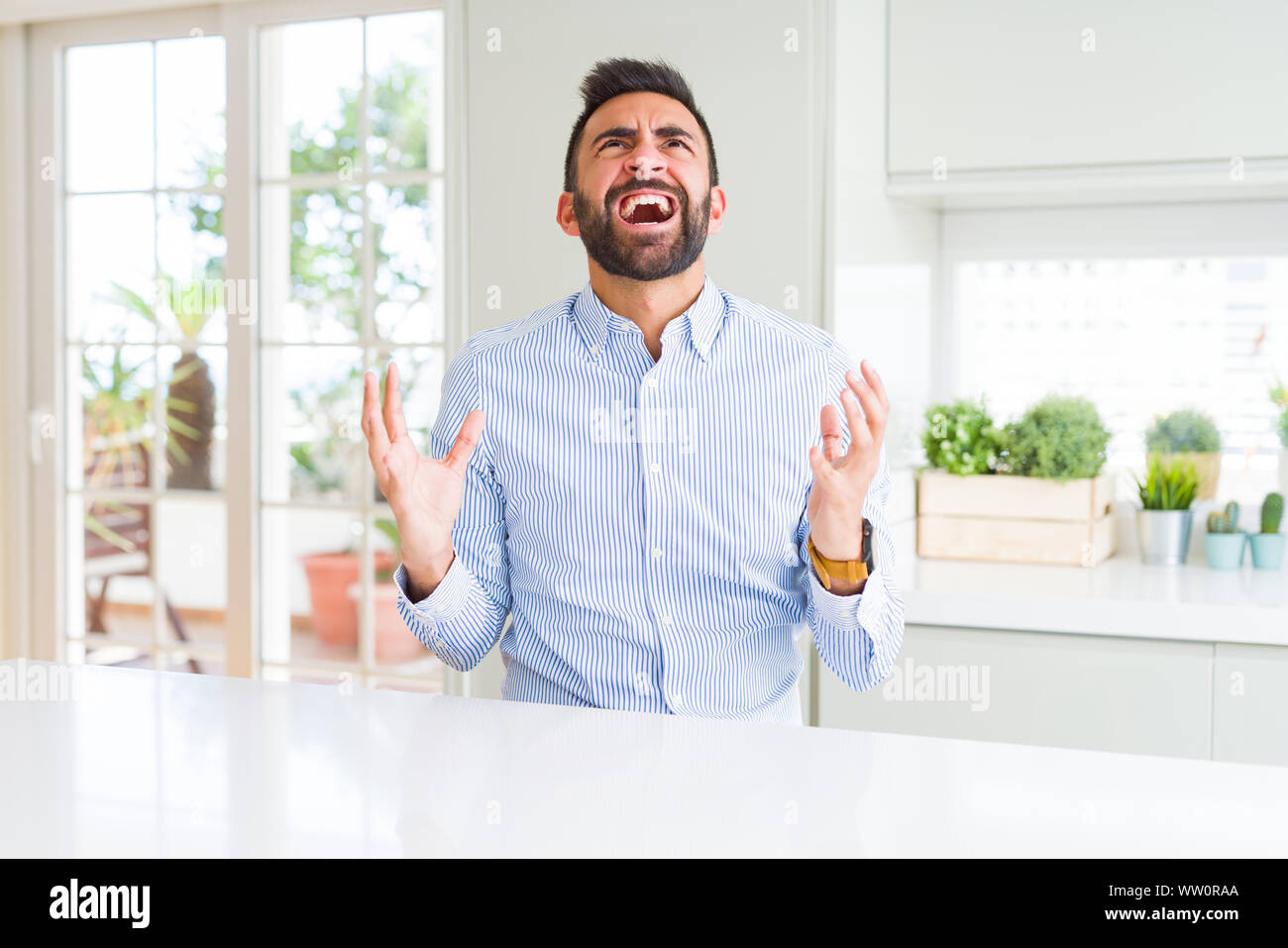 Handsome hispanic business man crazy and mad shouting and yelling with ...