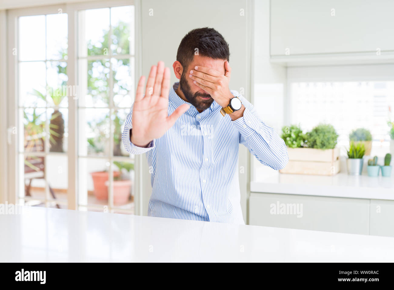Handsome hispanic business man covering eyes with hands and doing stop ...