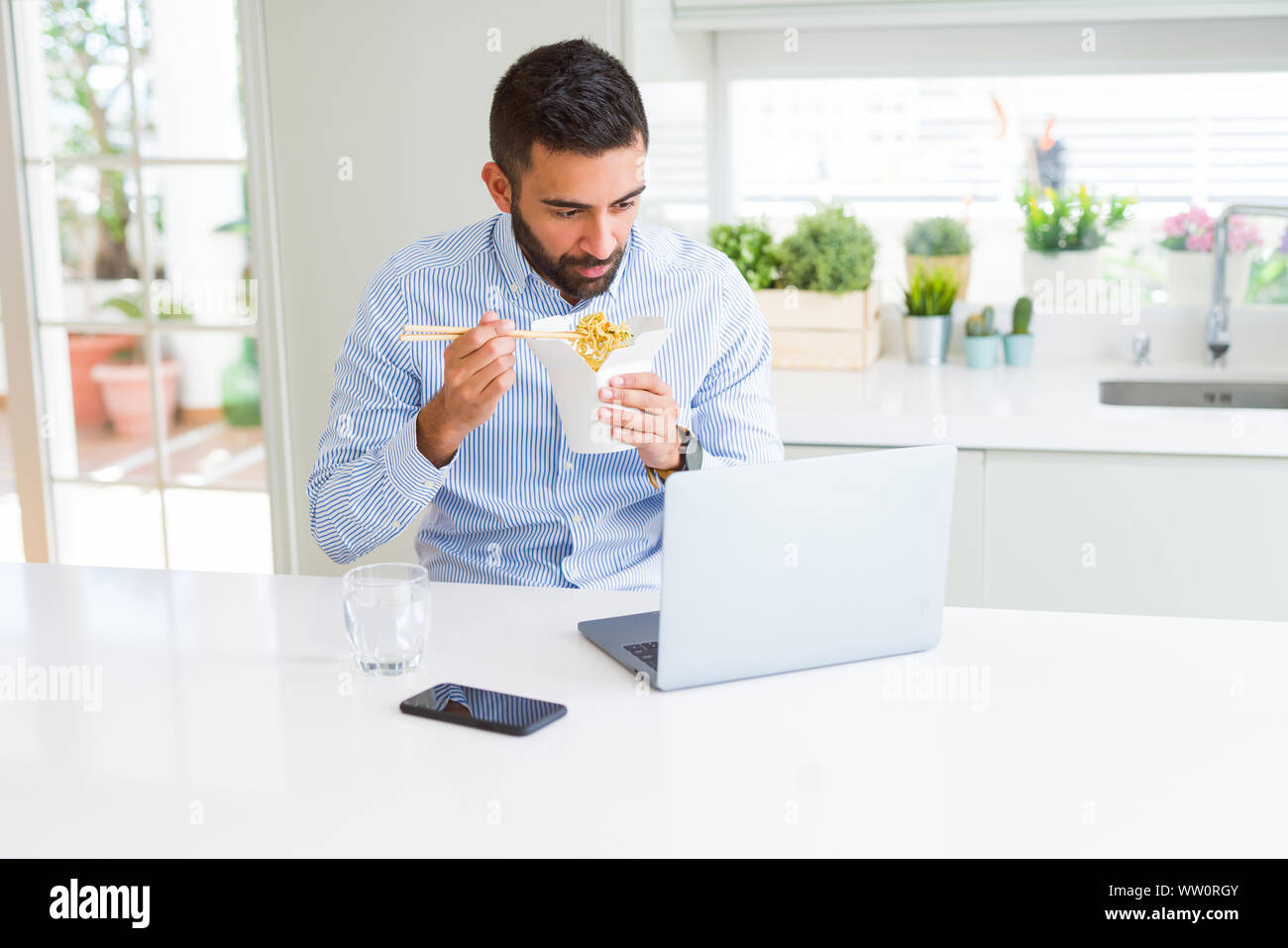 Business man eating asian food from delivery while working using ...