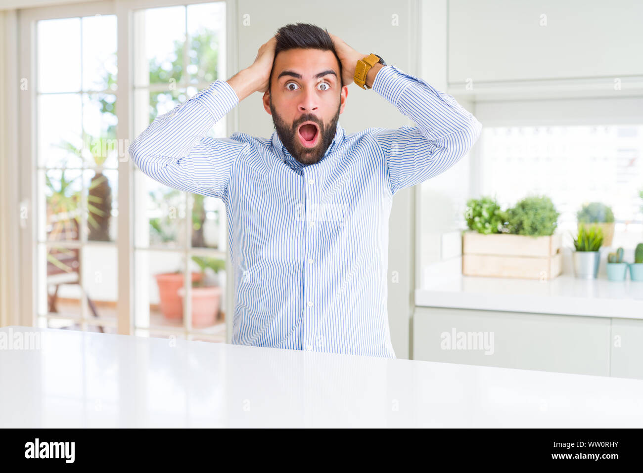 Handsome hispanic business man Crazy and scared with hands on head ...
