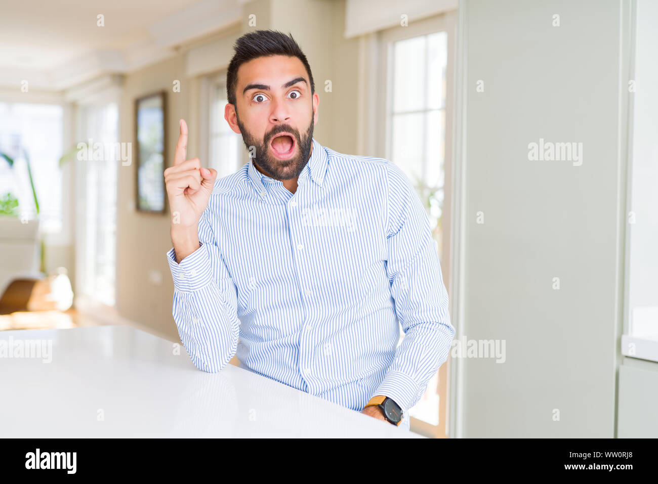 Handsome hispanic business man pointing finger up with successful idea ...
