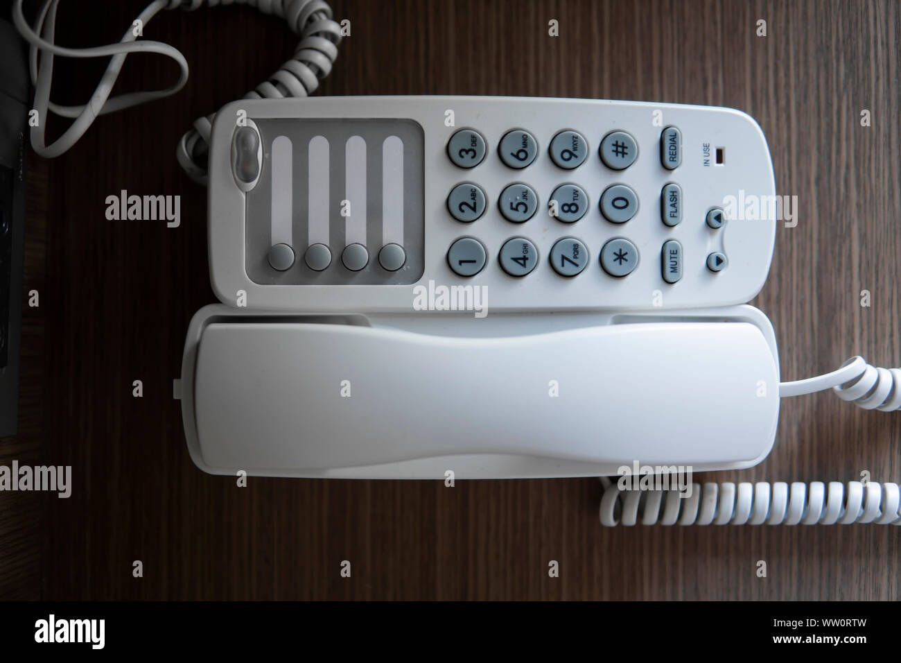 White vintage telephone with grey battoms on a brown table in hotel ...