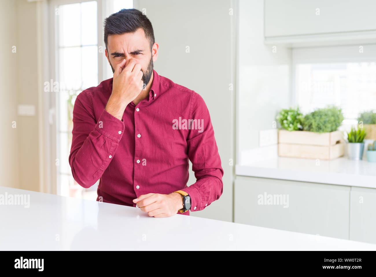 Handsome hispanic business man smelling something stinky and disgusting ...