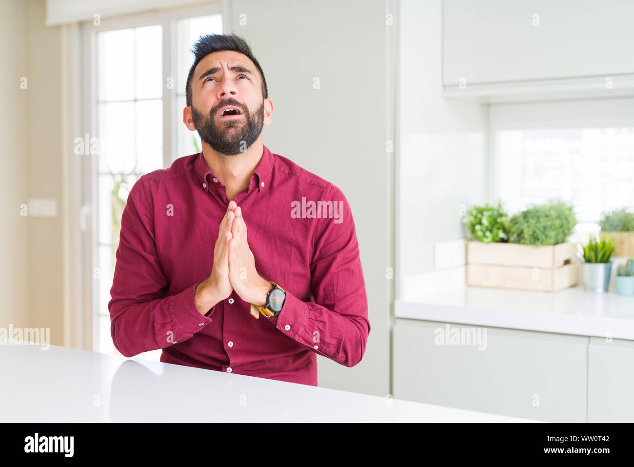 Handsome hispanic business man begging and praying with hands together ...