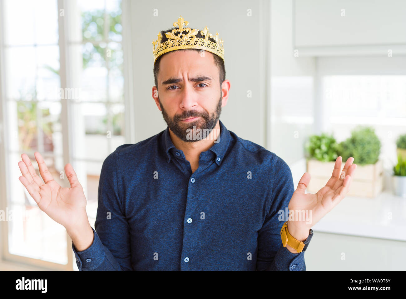 Handsome hispanic man wearing golden crown over head as the king ...