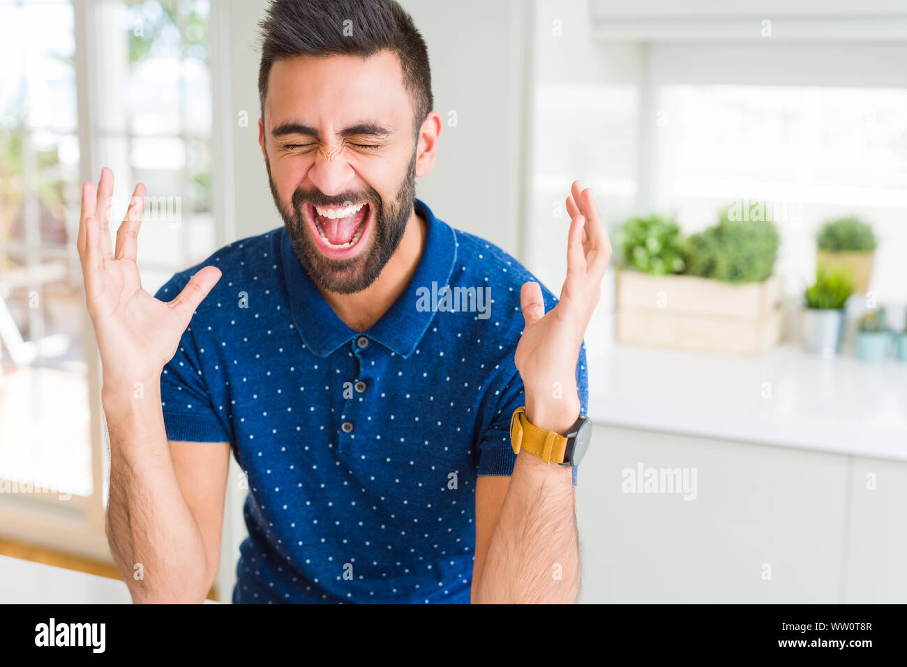 Handsome hispanic man at home celebrating mad and crazy for success ...