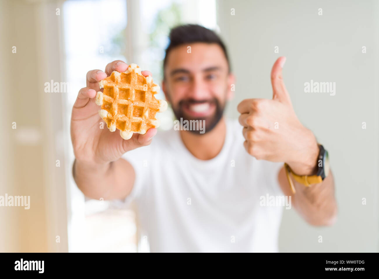 Handsome hispanic man eating sweet belgian waffle pastry happy with big ...