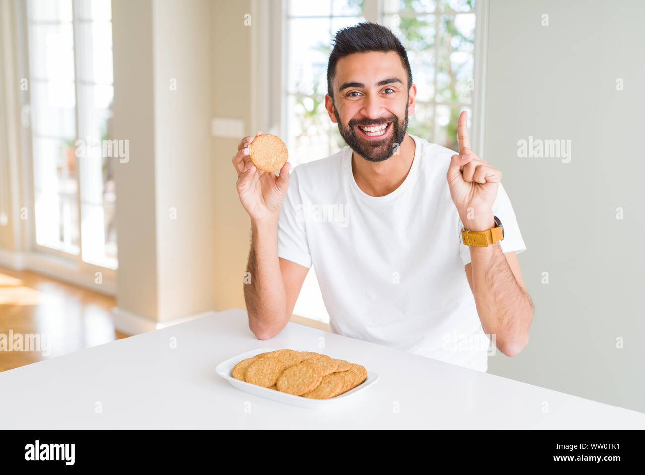 Handsome hispanic man eating healthy whole grain biscuits surprised ...