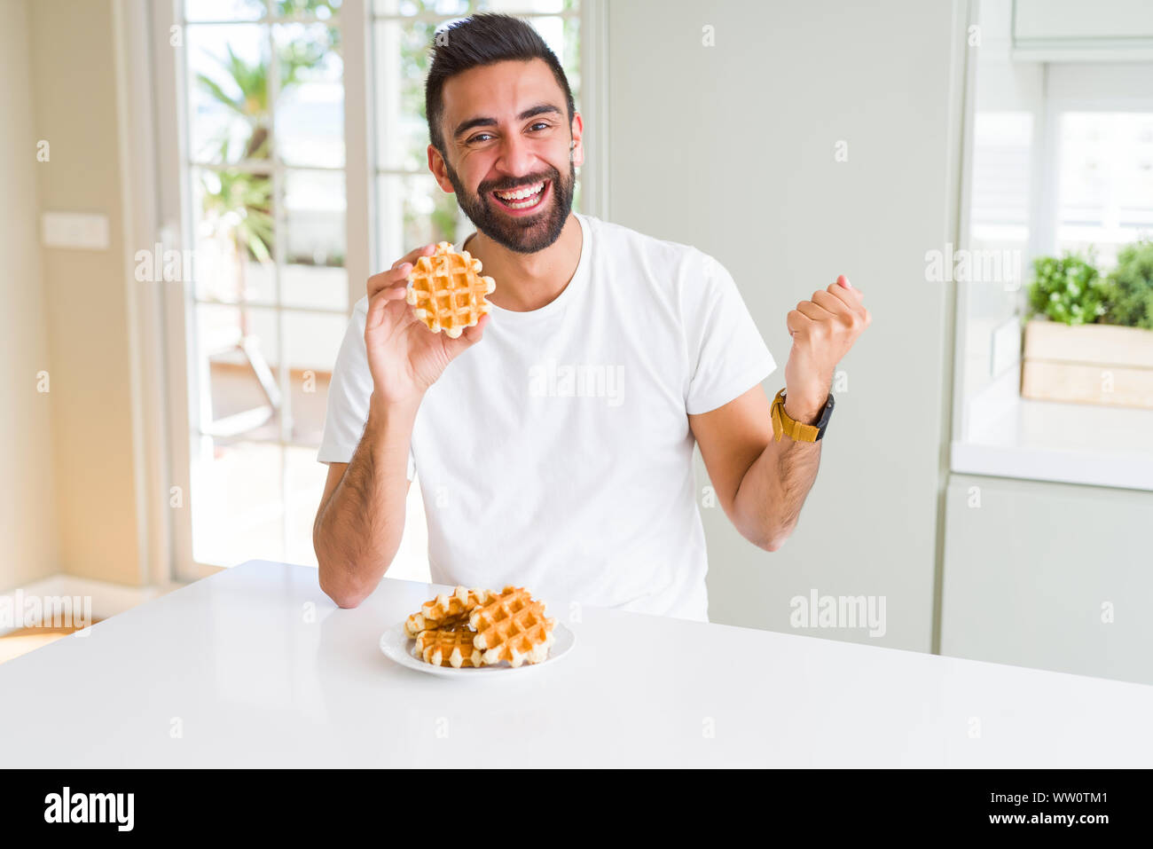Handsome hispanic man eating sweet belgian waffle pastry screaming ...