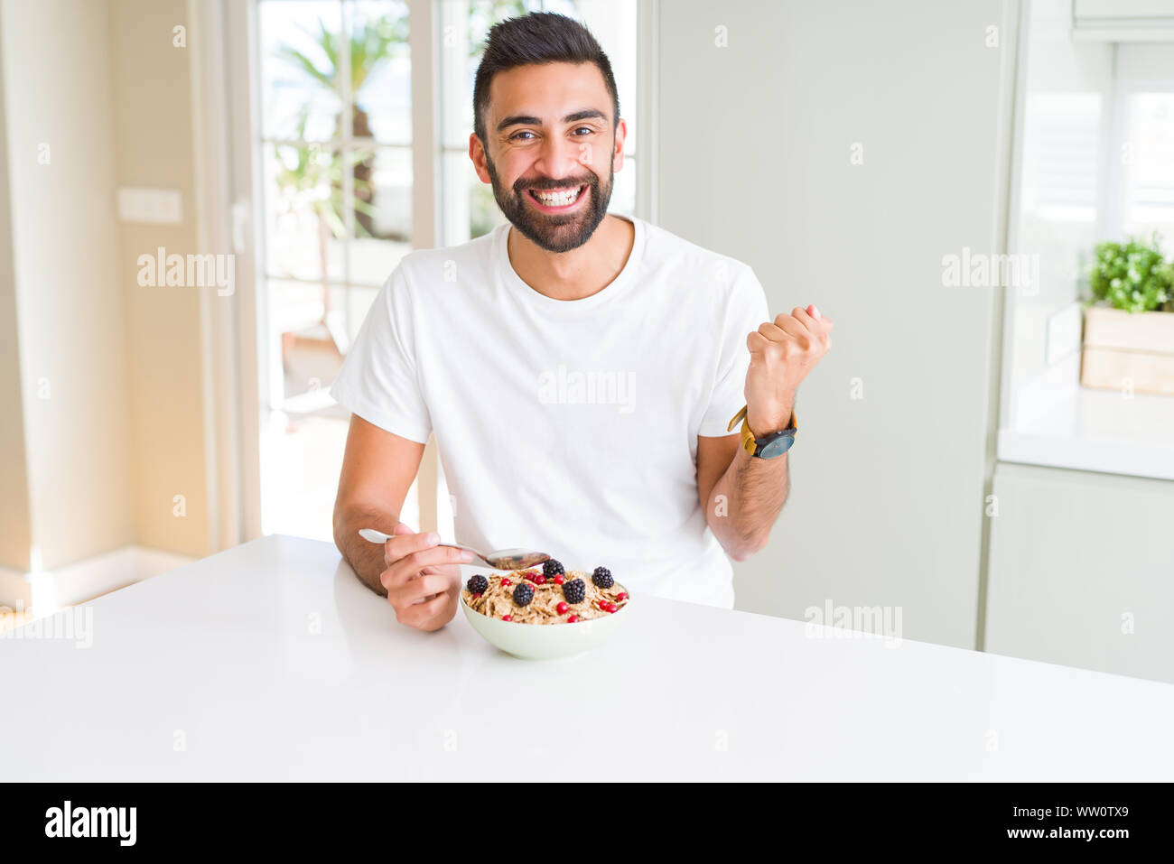 Handsome hispanic man eating healthy breakfast in the morning at home ...