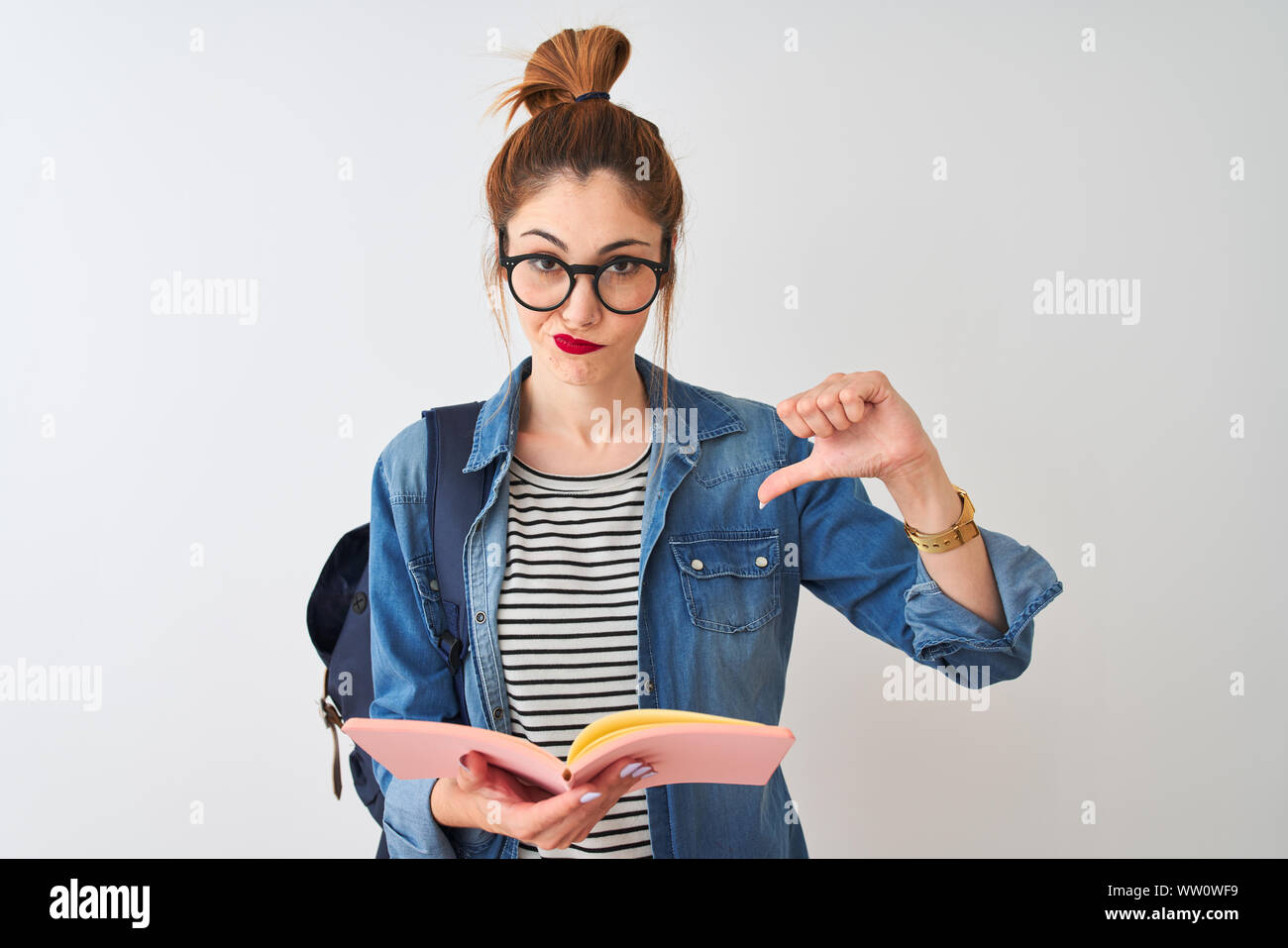 Redhead student woman wearing backpack reading book over isolated white ...