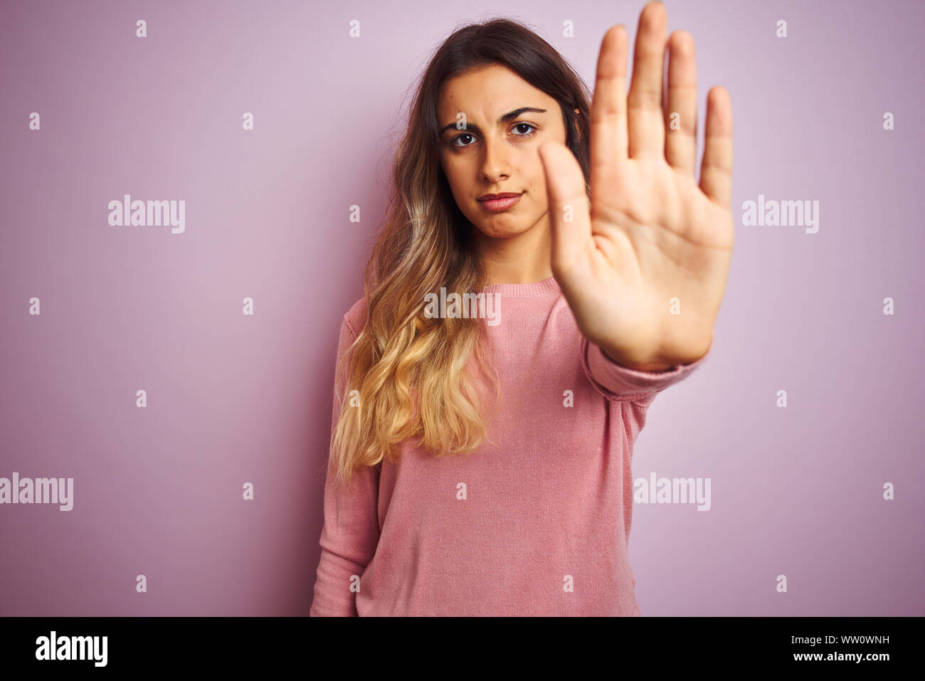Young beautiful woman wearing a sweater over pink isolated background ...