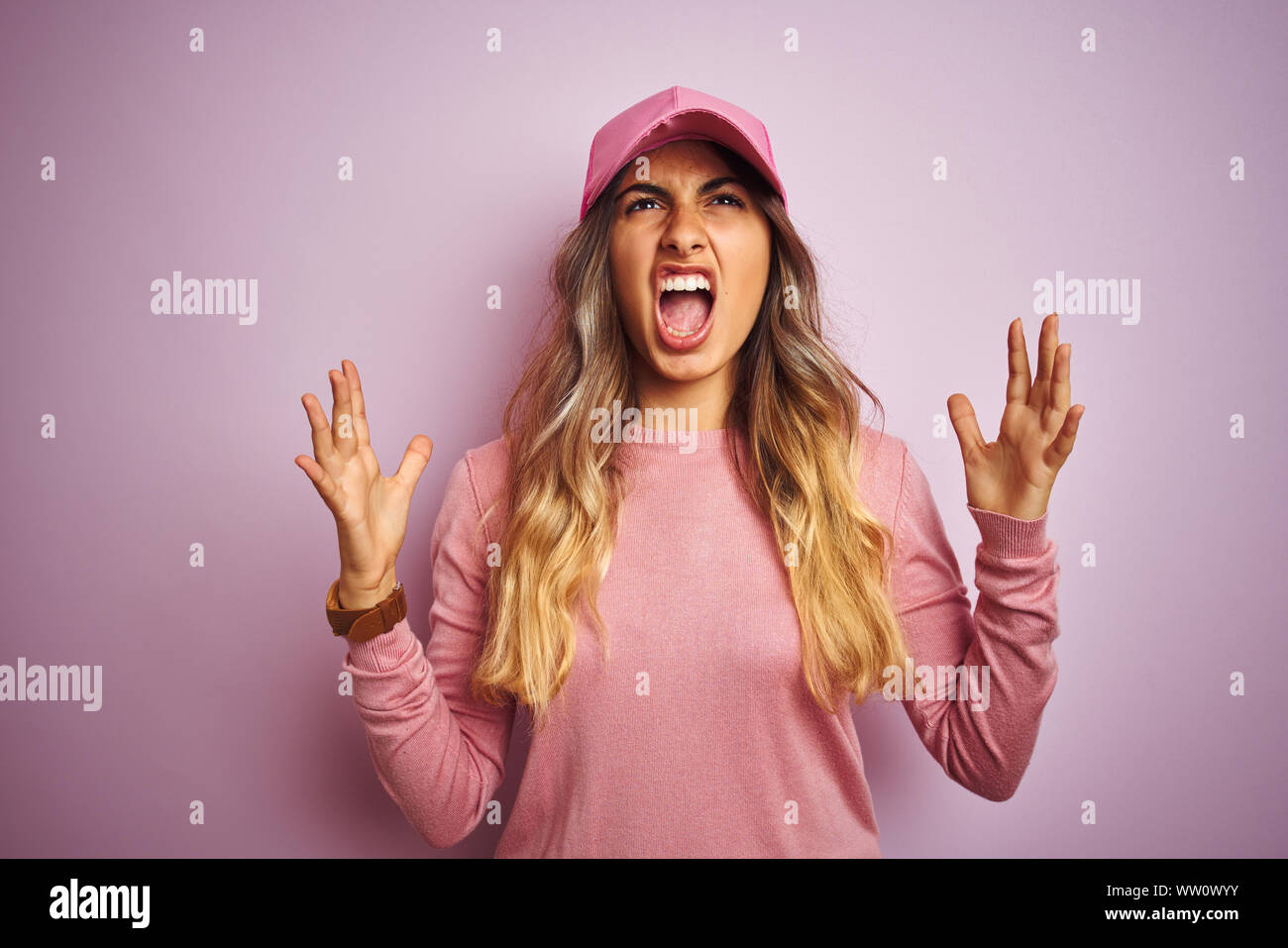 Young beautiful woman wearing cap over pink isolated background crazy ...