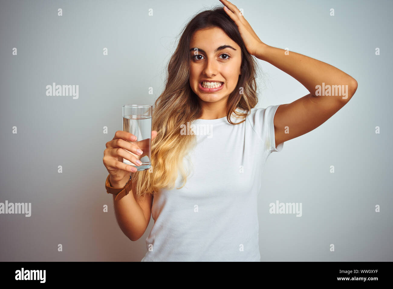Young beautiful woman drinking a glass of water over white isolated ...