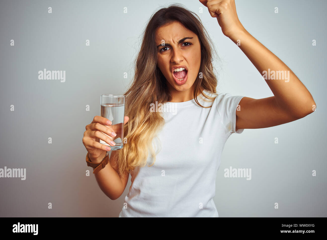 Young beautiful woman drinking a glass of water over white isolated ...
