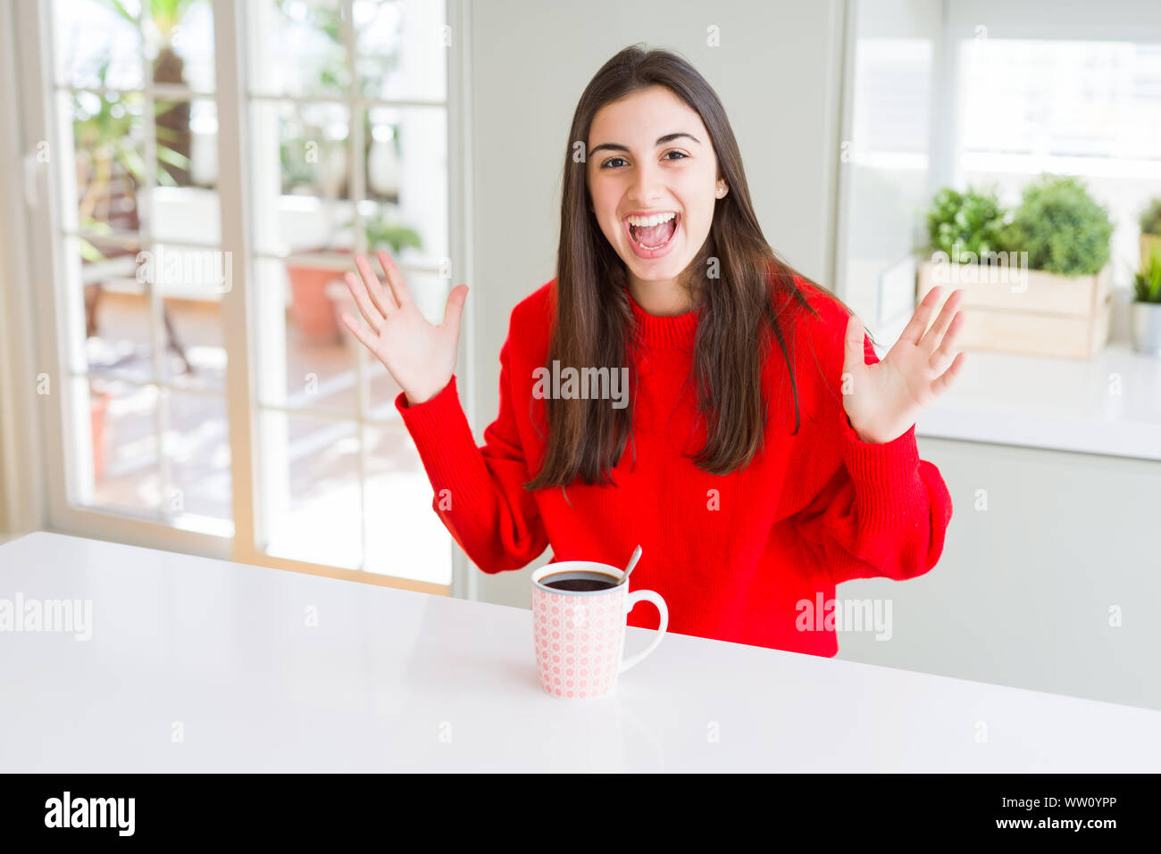 Beautiful young woman drinking a cup of black coffee celebrating crazy ...