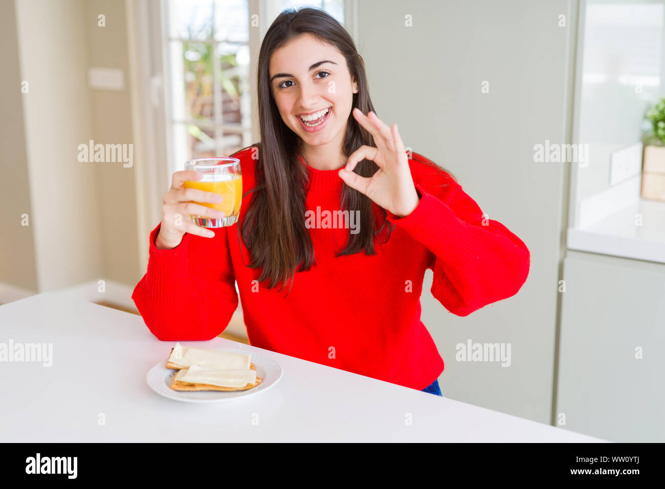 Beautiful young woman eating toasts and orange juice for snack or ...