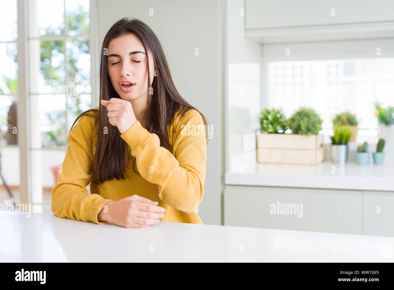 Beautiful young woman wearing yellow sweater feeling unwell and ...