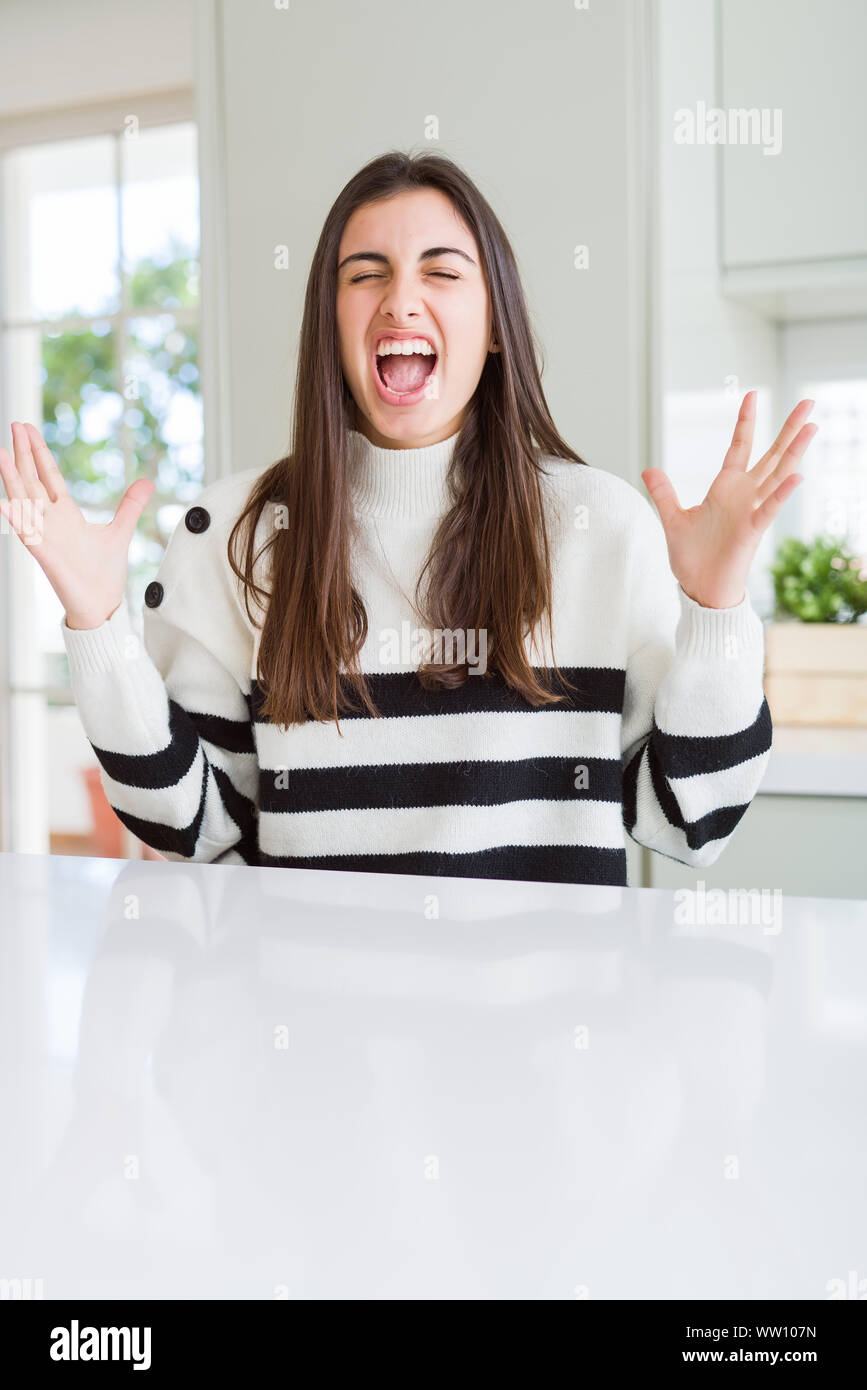 Beautiful young woman wearing stripes sweater crazy and mad shouting ...