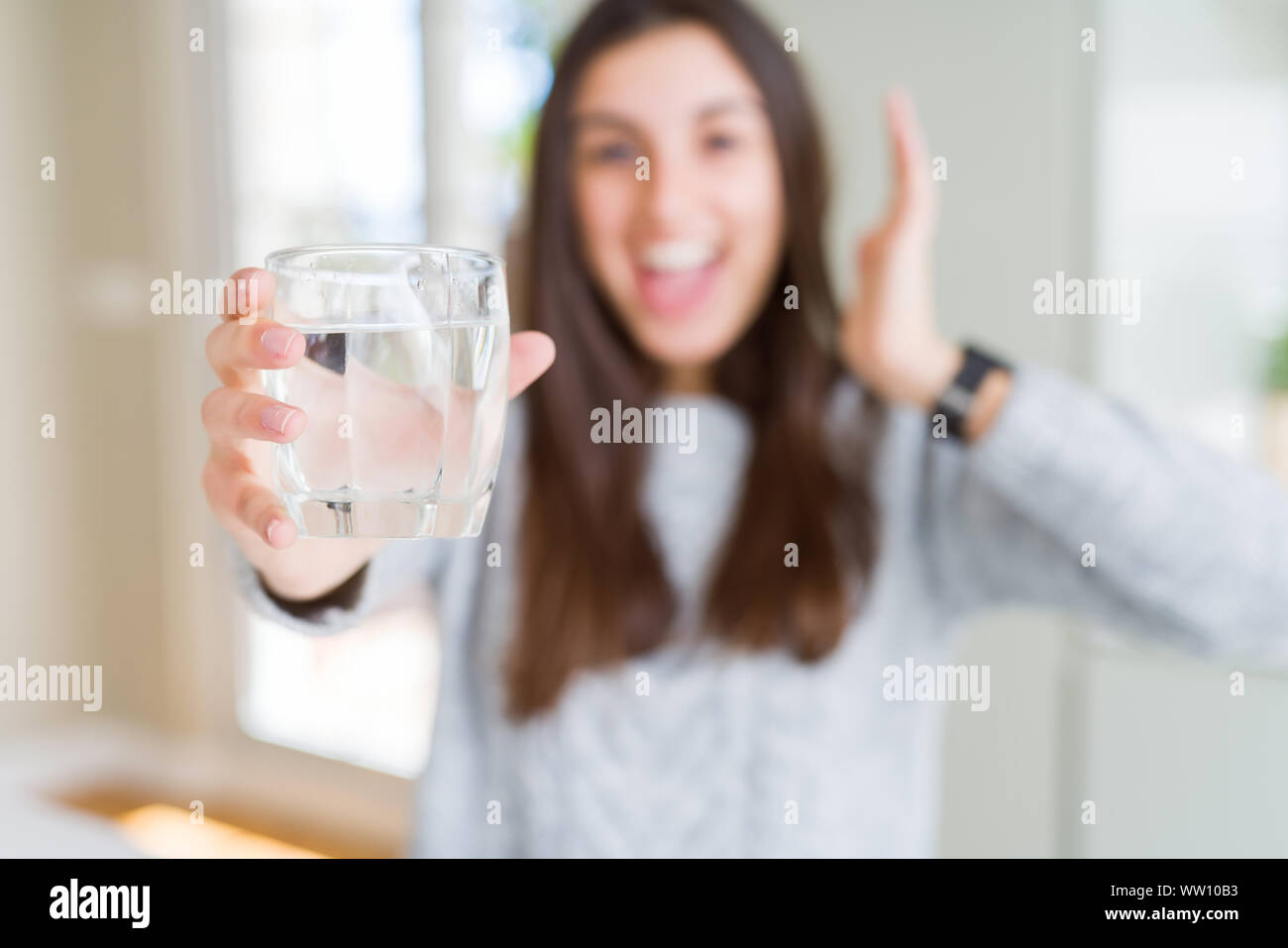 Beautiful young woman drinking a fresh glass of water very happy and ...