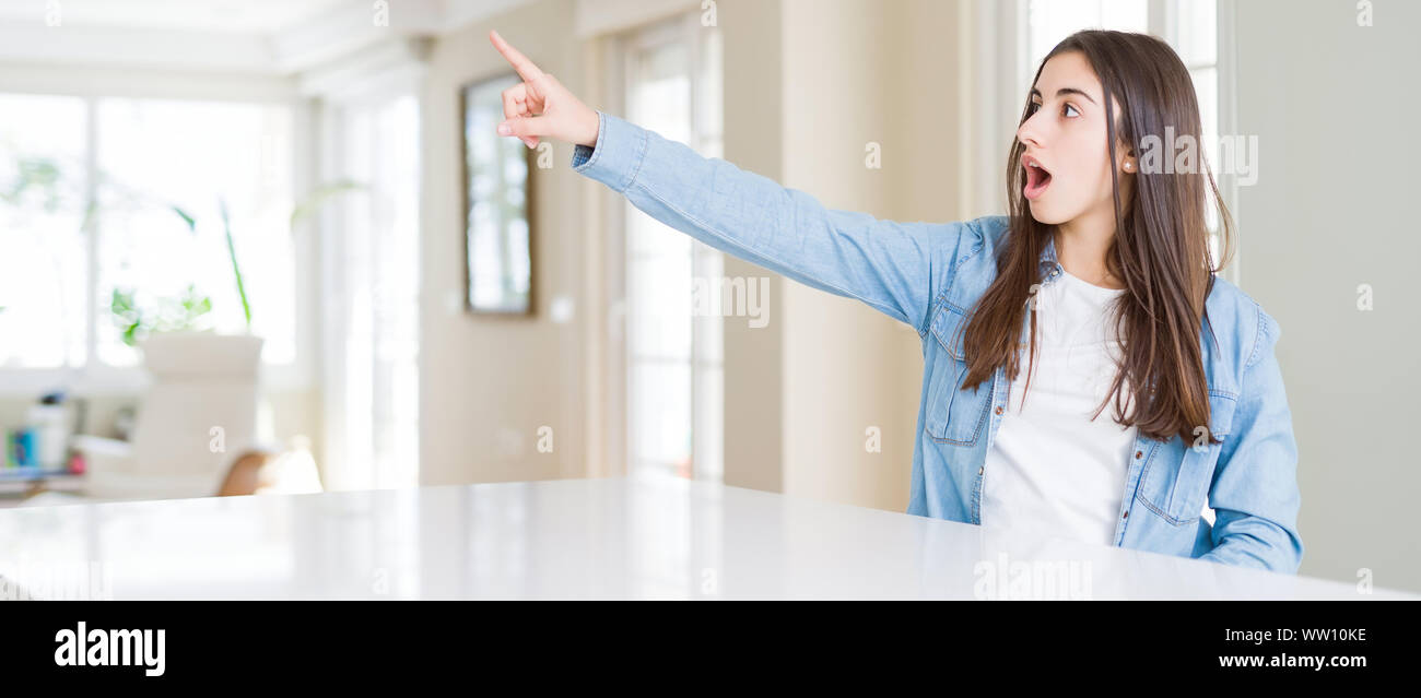 Wide angle picture of beautiful young woman sitting on white table at ...
