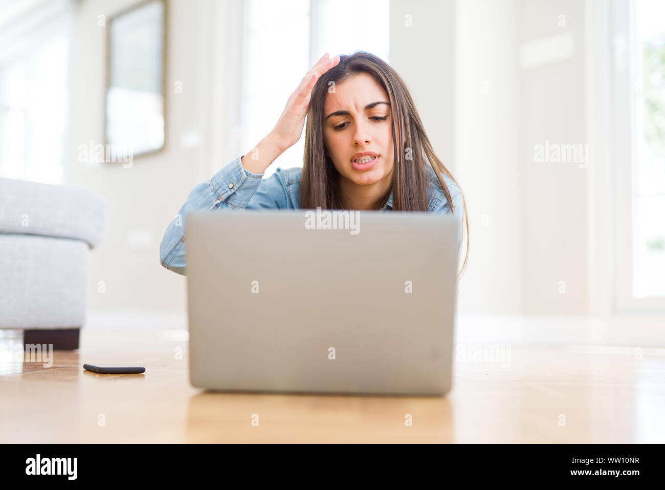 Beautiful young woman laying on the floor using laptop annoyed and ...