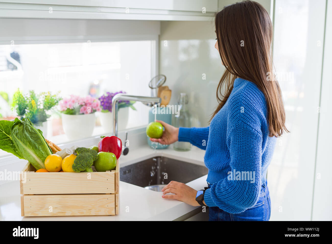 Young woman washing vegetables and fruit using water from sink Stock ...