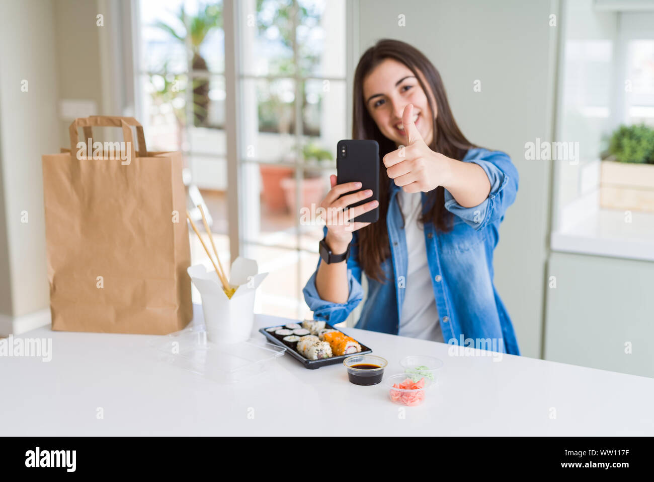 Beautiful young woman ordering food delivery from app using smartphone ...