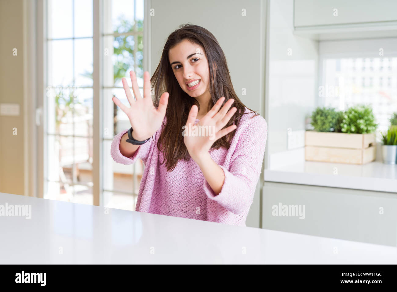 Beautiful young woman wearing pink sweater afraid and terrified with ...