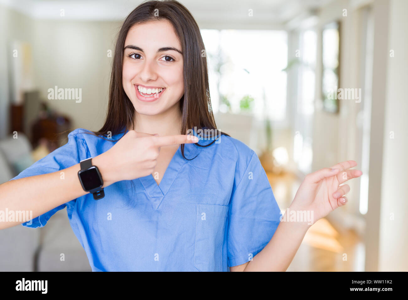 Beautiful young nurse woman at the clinic smiling and looking at the ...